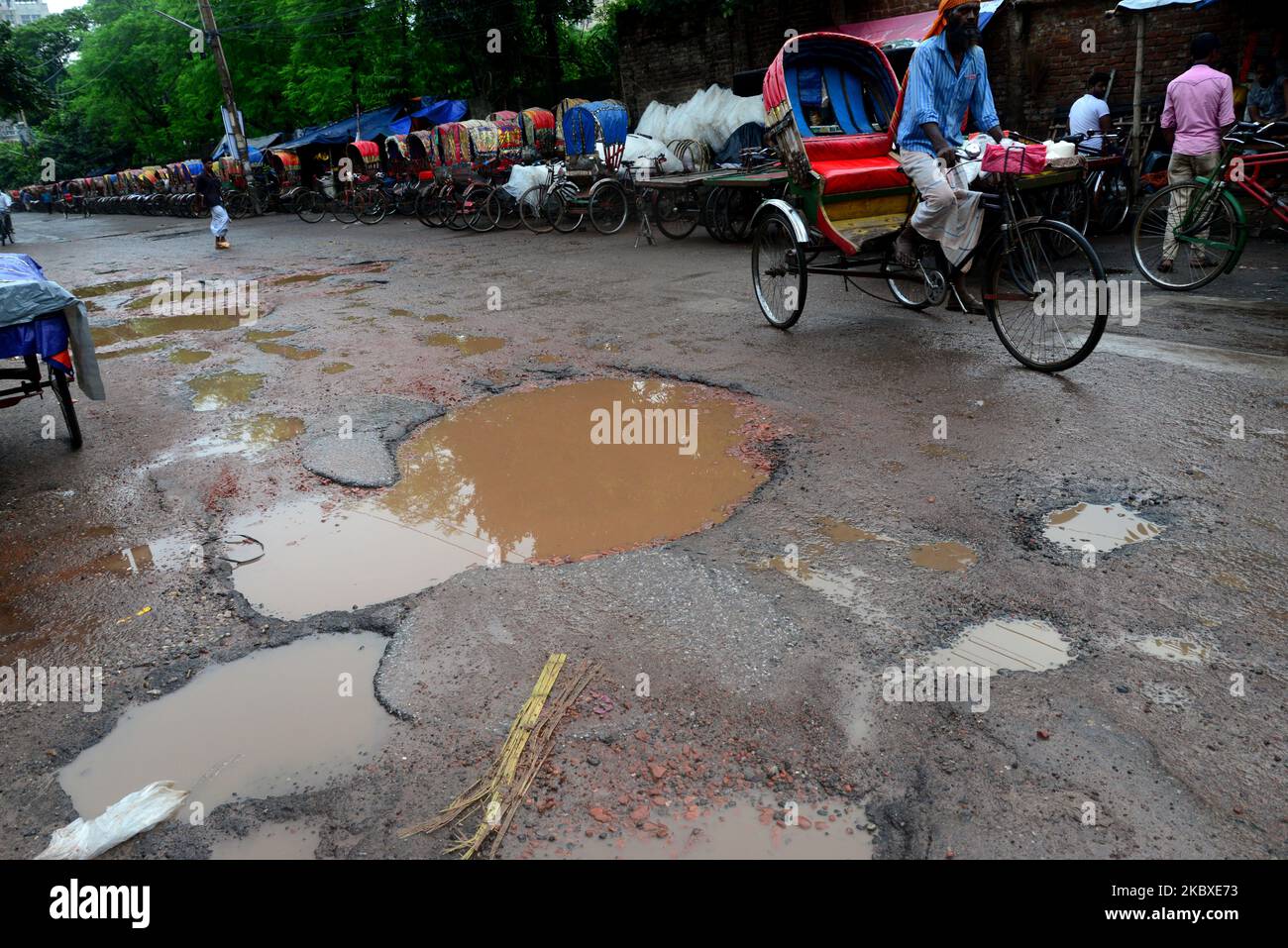 Vehicles and people trying to moves on the broken road in Dhaka City in ...