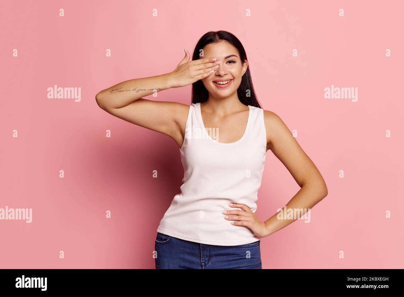 Happy woman with one eye closed smiling isolated on trendy pink studio ...