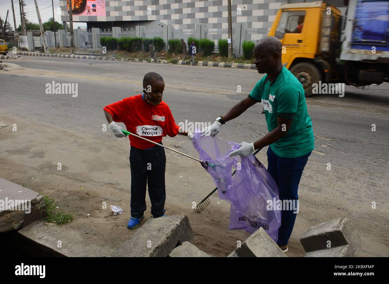 A young environmental activist and a volunteer carries waste in a ...