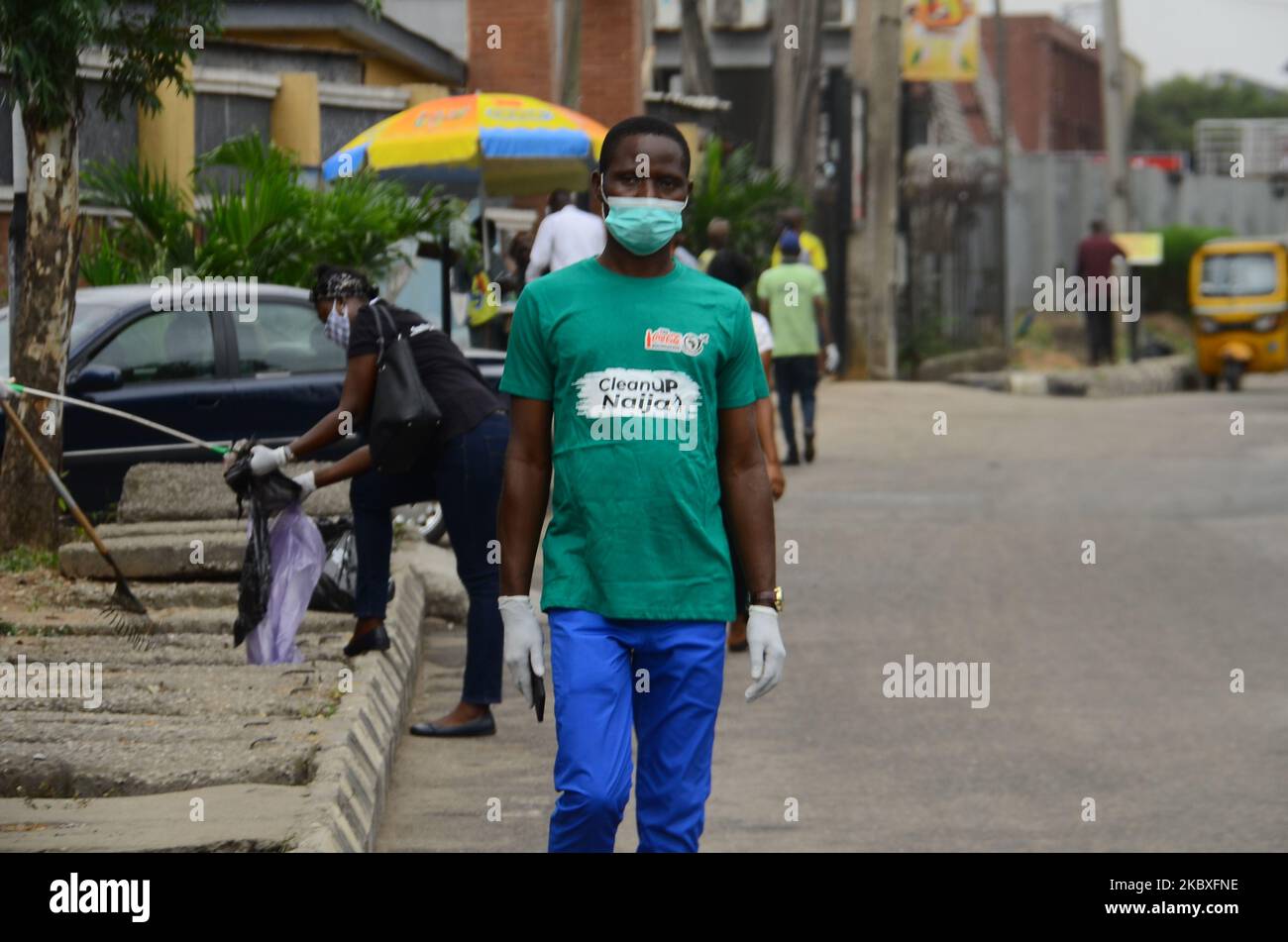 A volunteer with a face mask walk pass other volunteers cleaning ...