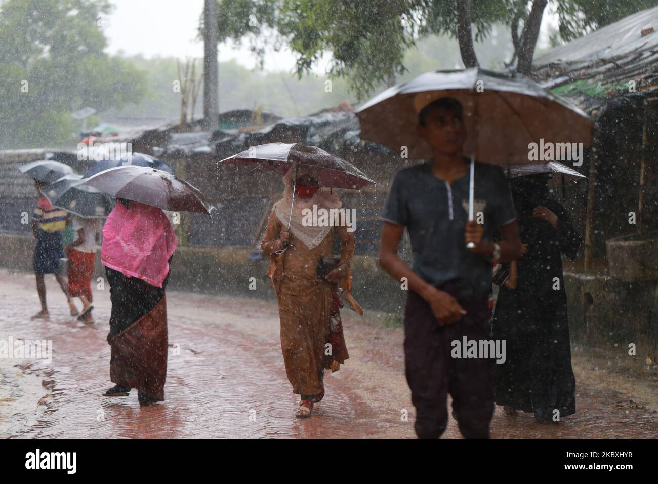 Rohingya refugees walk during a monsoon rain at Kutupalong refugee camp ...