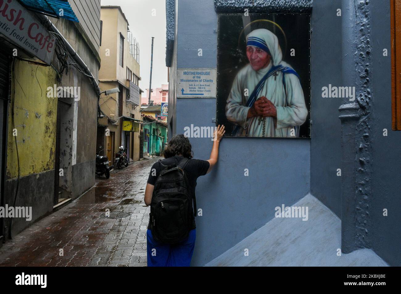 A lady pray in front of a picture of Saint Teresa , outside ...