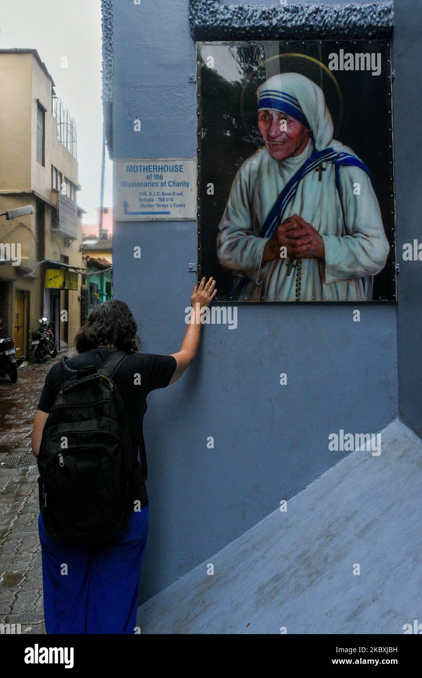 A lady pray in front of a picture of Saint Teresa , outside ...