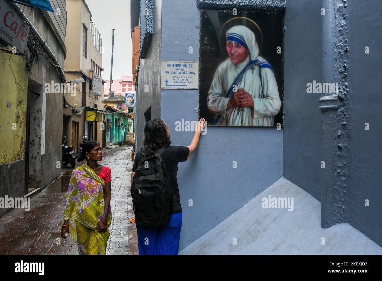 A lady pray in front of a picture of Saint Teresa , outside ...