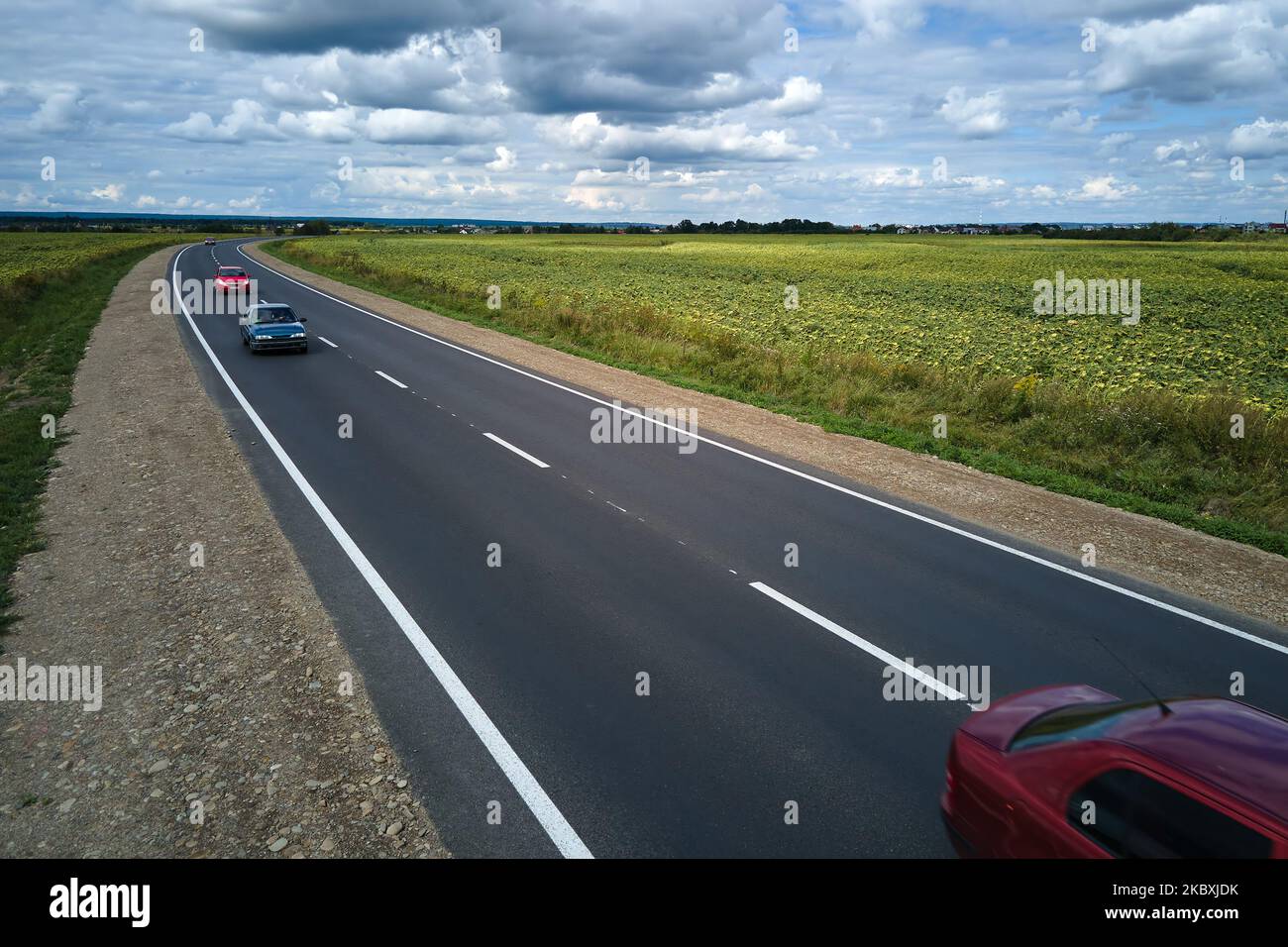 Aerial view of intercity road between green agricultural fields with ...