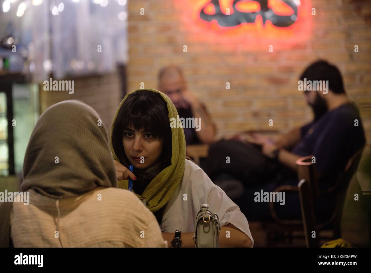 Iranian youth who do not use protective face maks sit in a cafe in ...