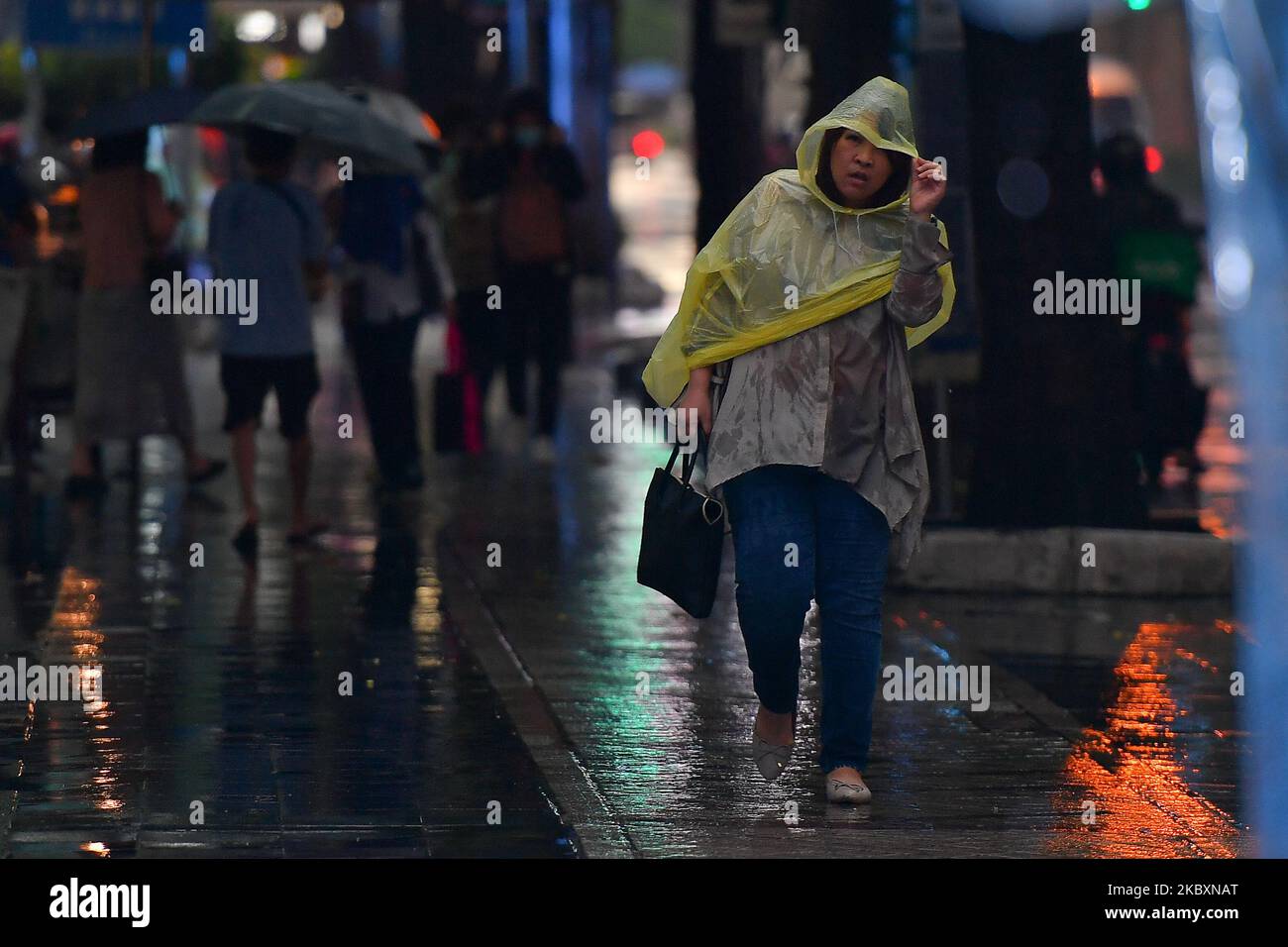 A office worker wearing a rain suit during rush hour while rainfall in ...