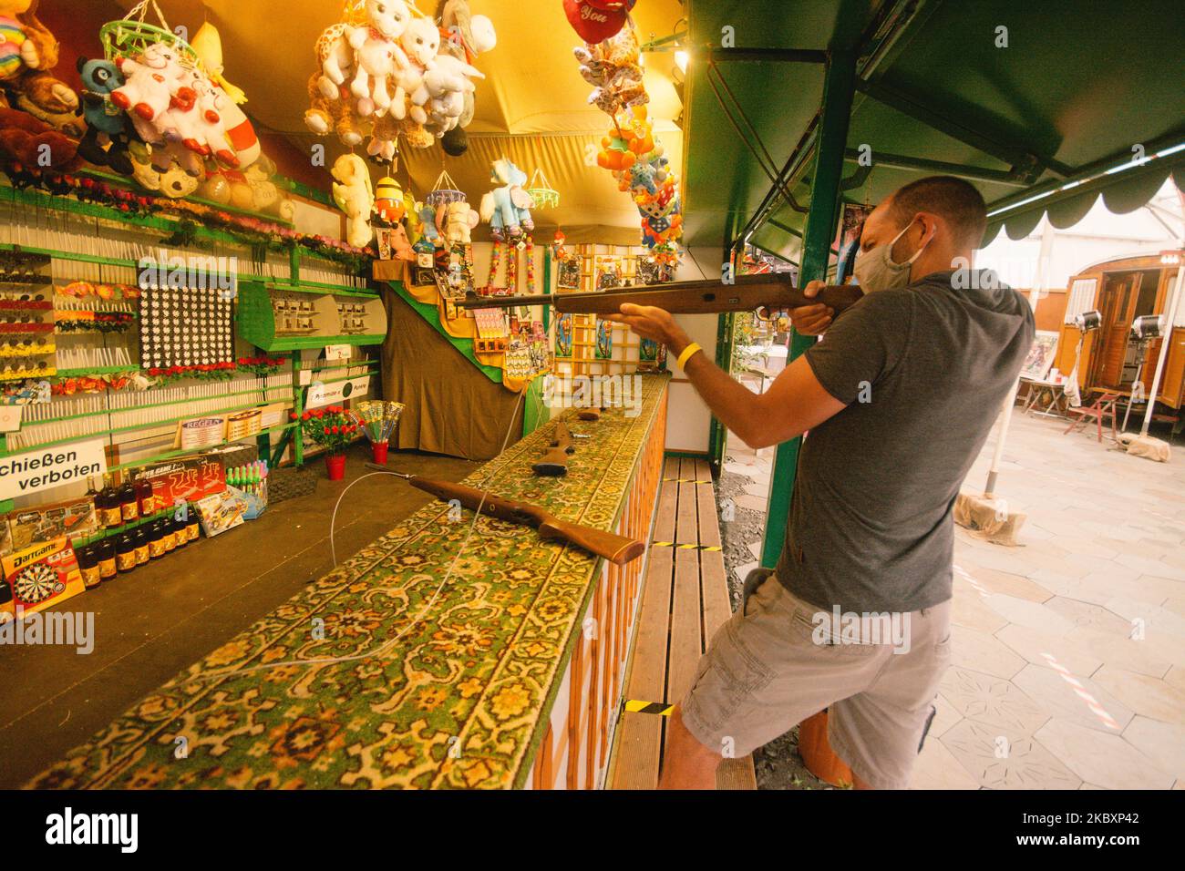 A visitor with face mask aims in a shooting range at the opening day of ...