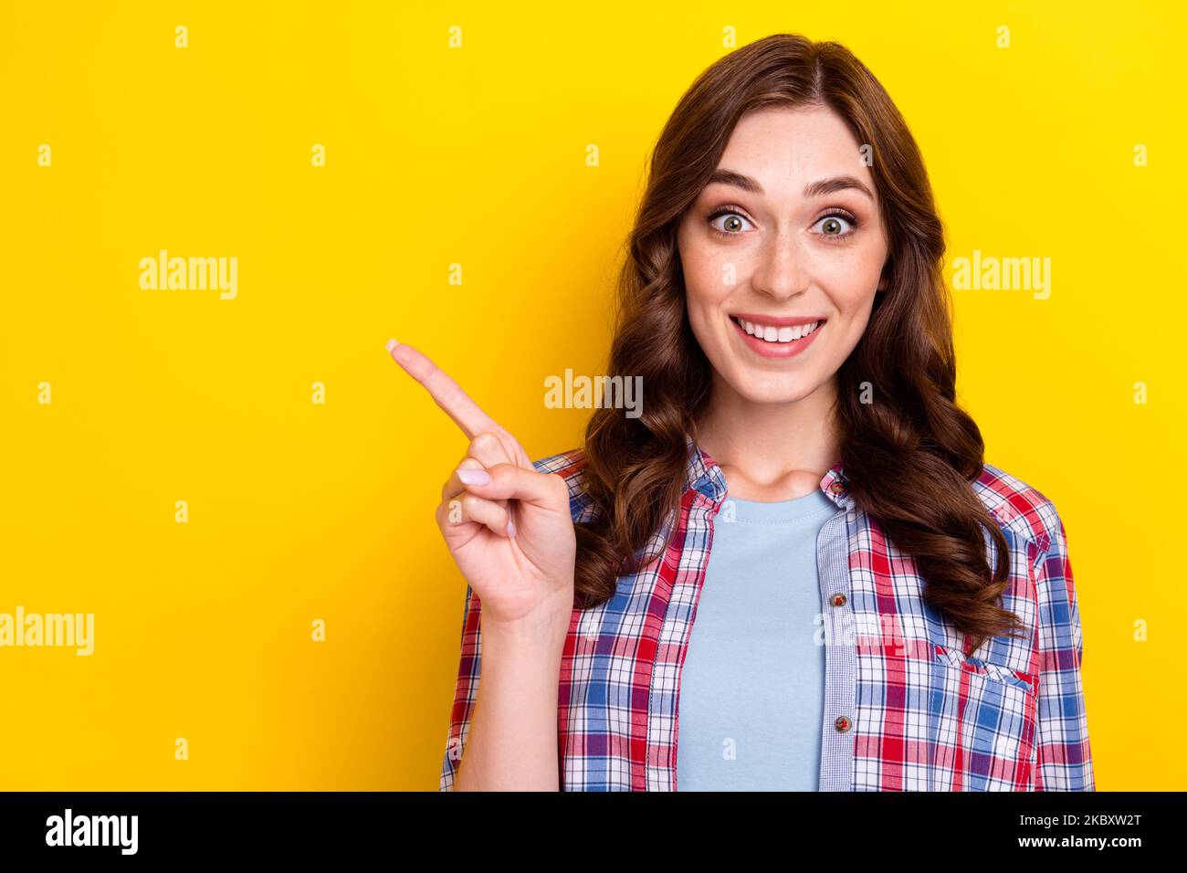 Photo of pretty impressed girl dressed checkered shirt pointing finger ...