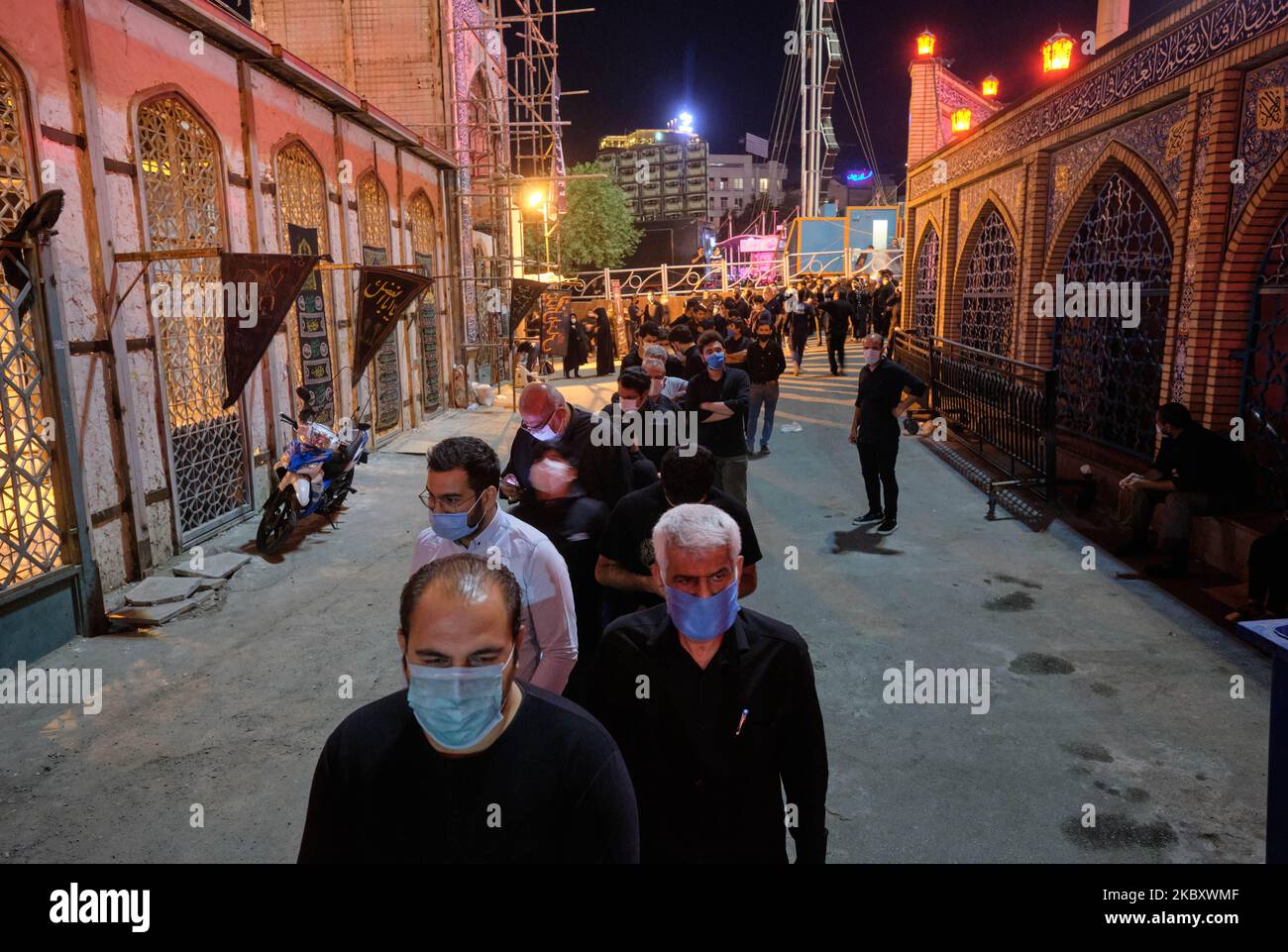 Iranian men wearing protective face masks line-up as they wait to enter ...