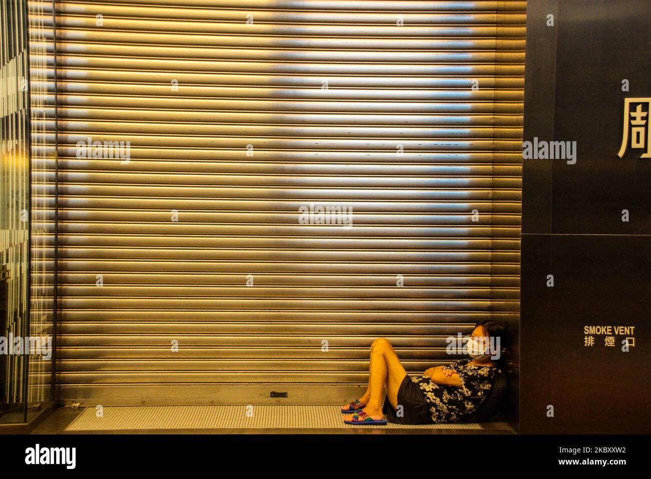 A local woman laying inside a shop shutter during street demonstrations ...