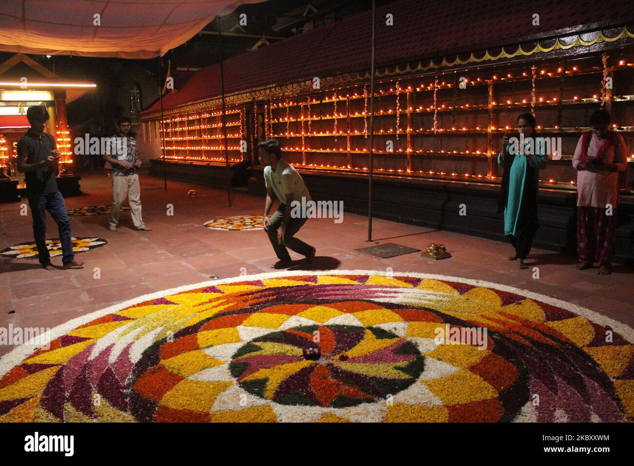 Malayali community members take photos around a giant Pookalam, a ...