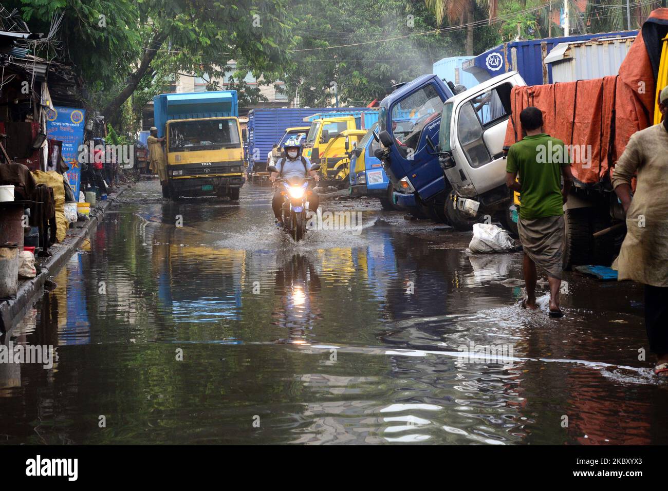 Commuters make their way along a waterlogged street following monsoon ...