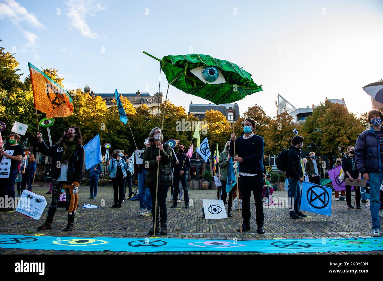 Hundreds of XR activists are standing up with eyes painting on placards ...