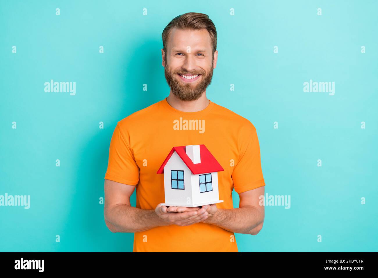 Photo of nice beard guy hold house wear orange t-shirt isolated on teal ...