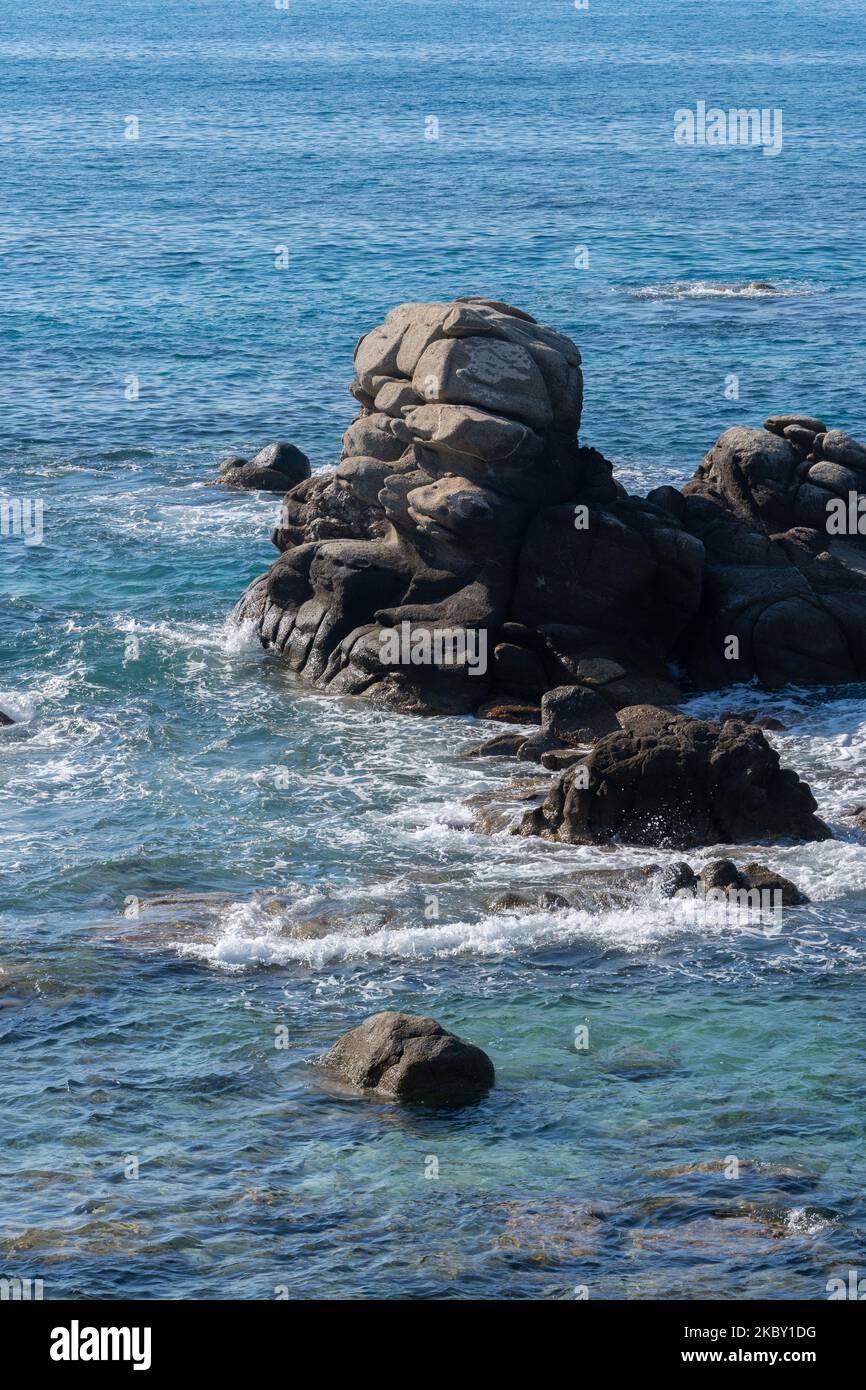 Wild rocky beach coastline and the sea, wave splashes on rock in sea ...