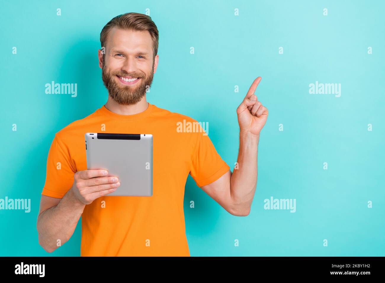 Photo of cool beard guy hold tablet index promo wear orange t-shirt ...