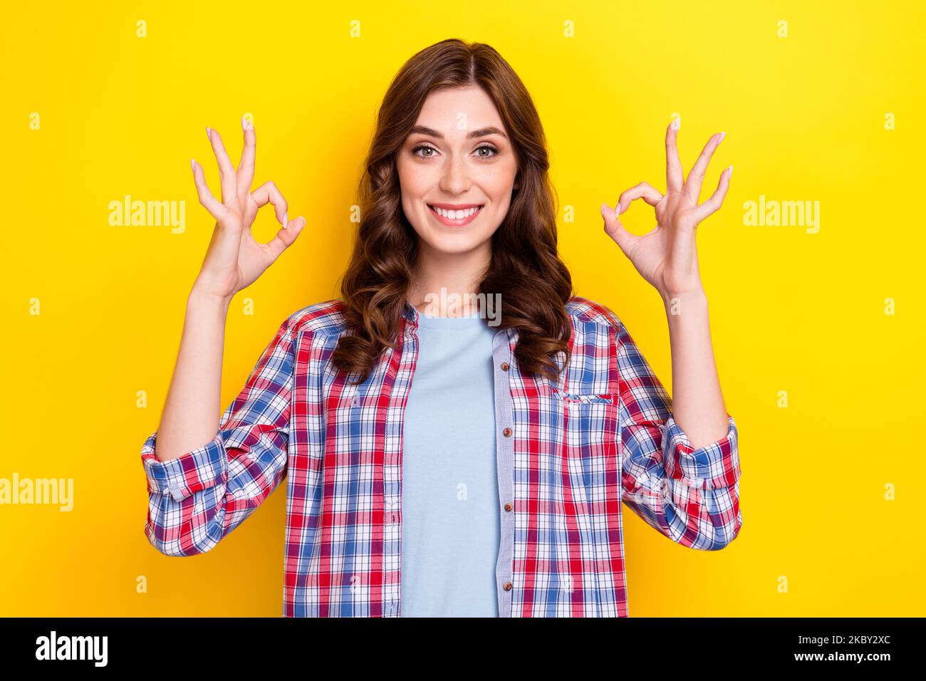 Photo of pretty shiny young girl dressed checkered showing two okey ...
