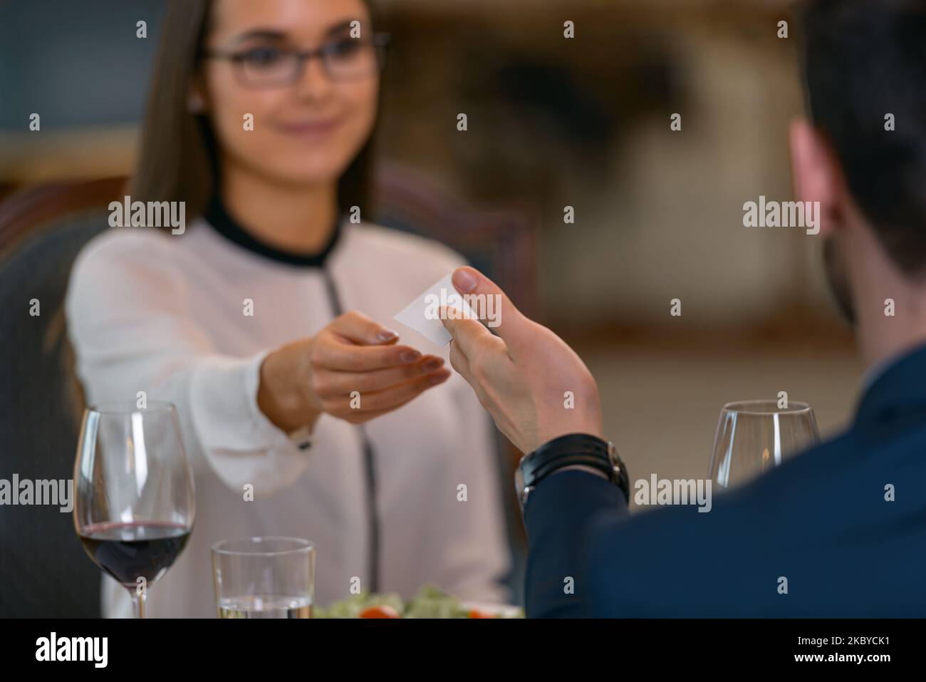 Businessman giving his visit card to woman while having dinner in ...
