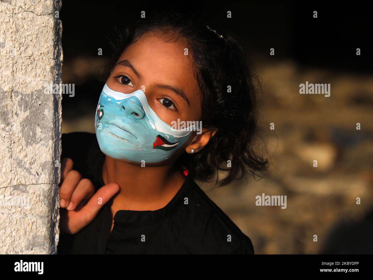 Osama, a Palestinian artist, paints a mask on the face of a young girl ...