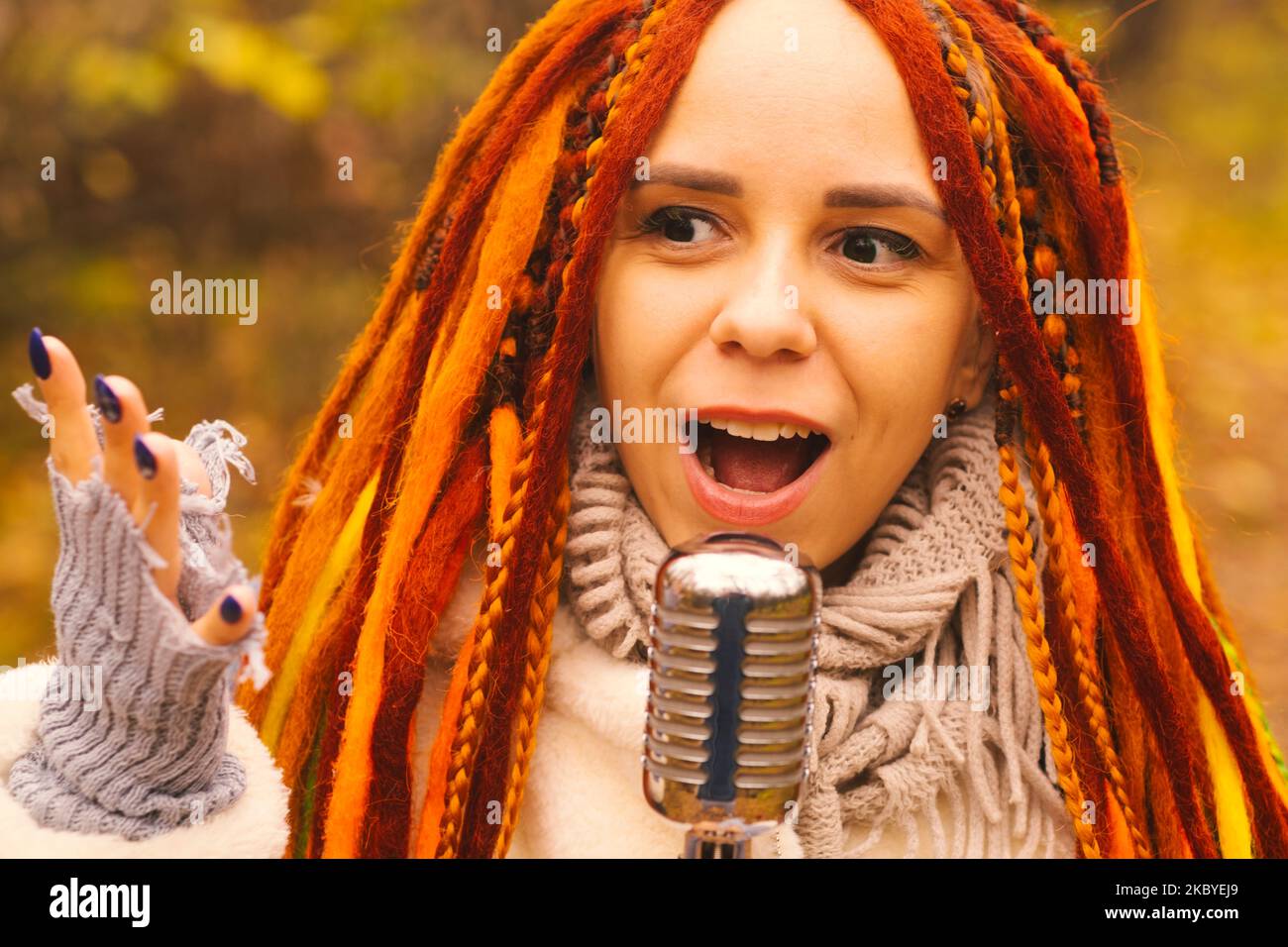 Young woman with bright hairstyle with retro microphone in autumn ...