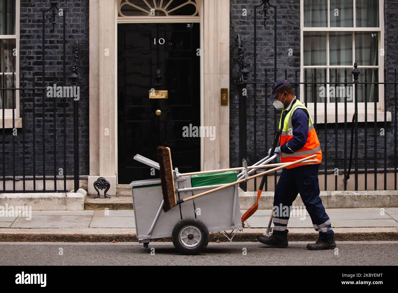 A street sweeper pushes his cart past No 10. Downing Street in London ...