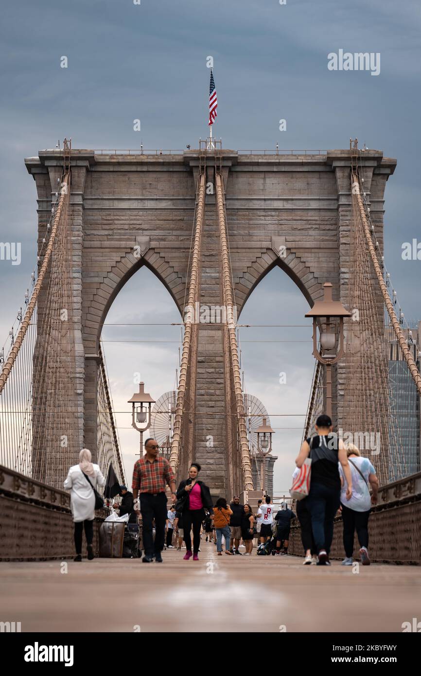 A low angle shot of the Brooklyn Bridge with people walking around in ...