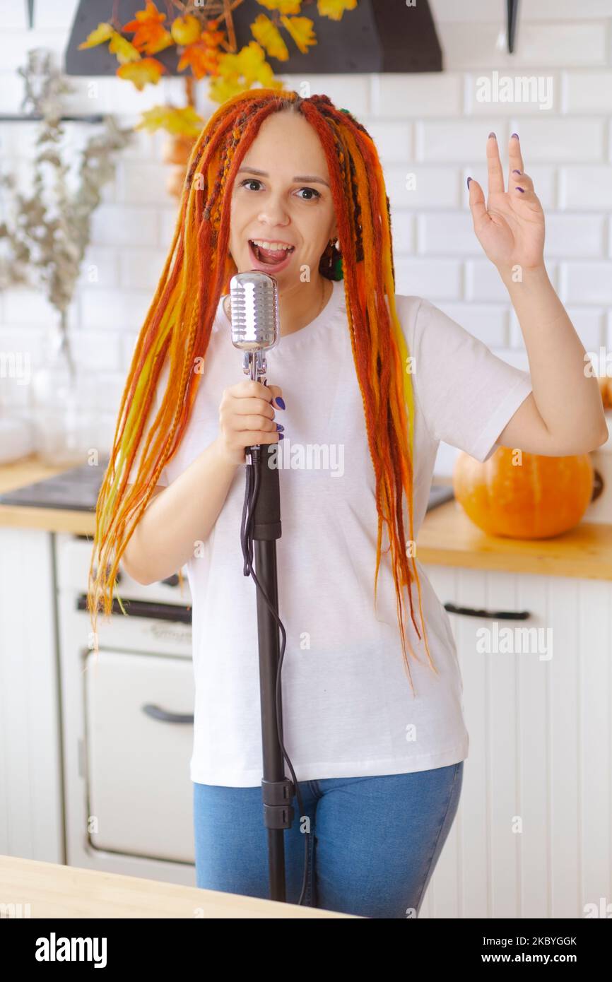 Young woman with bright hairstyle with retro microphone in kitchen ...