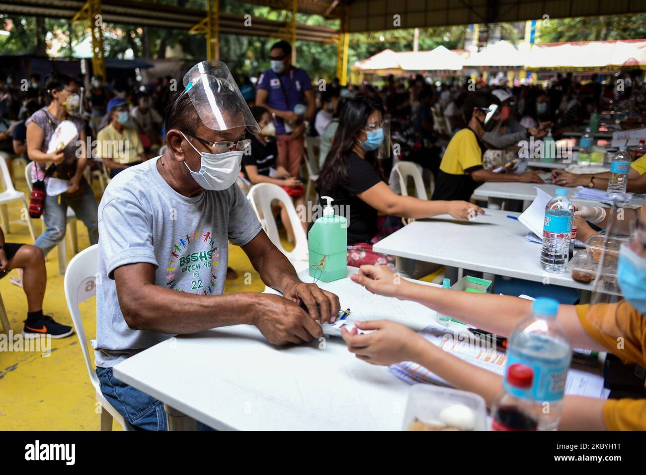 A man wearing a face mask and a face shield is assisted during the ...