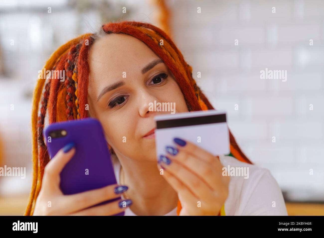 Young woman with bright dreadlocks with mobile phone, credit card ...