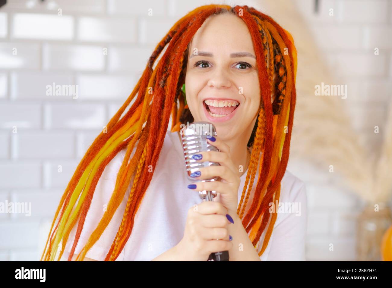 Young woman with bright hairstyle with retro microphone in kitchen ...