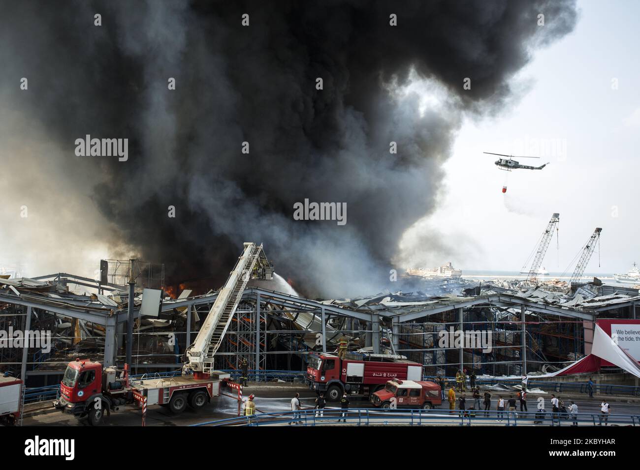 Firefighters try to douse flames billowing from a huge fire that broke ...