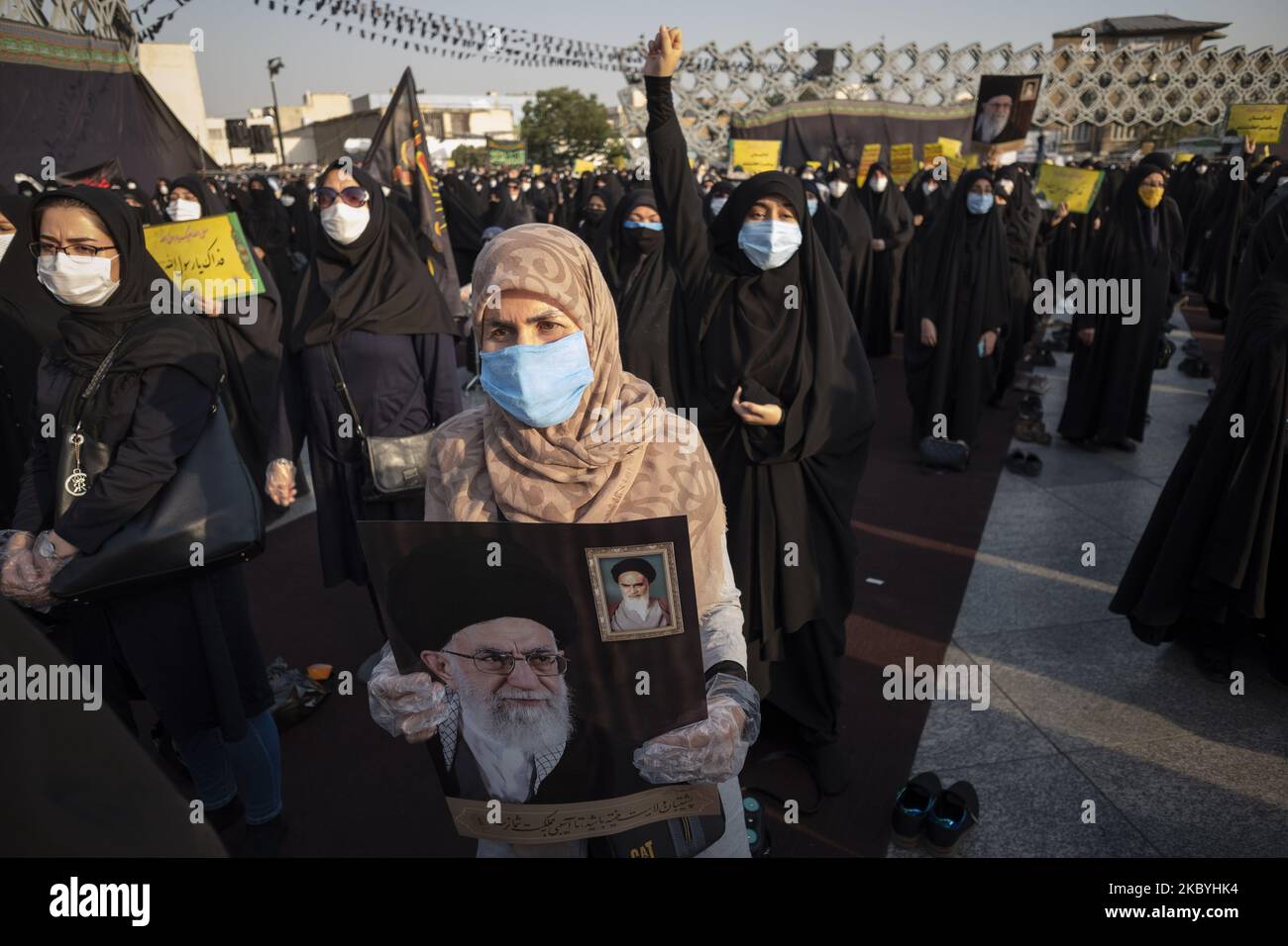An Iranian veiled woman wearing a protective face mask holds portraits ...