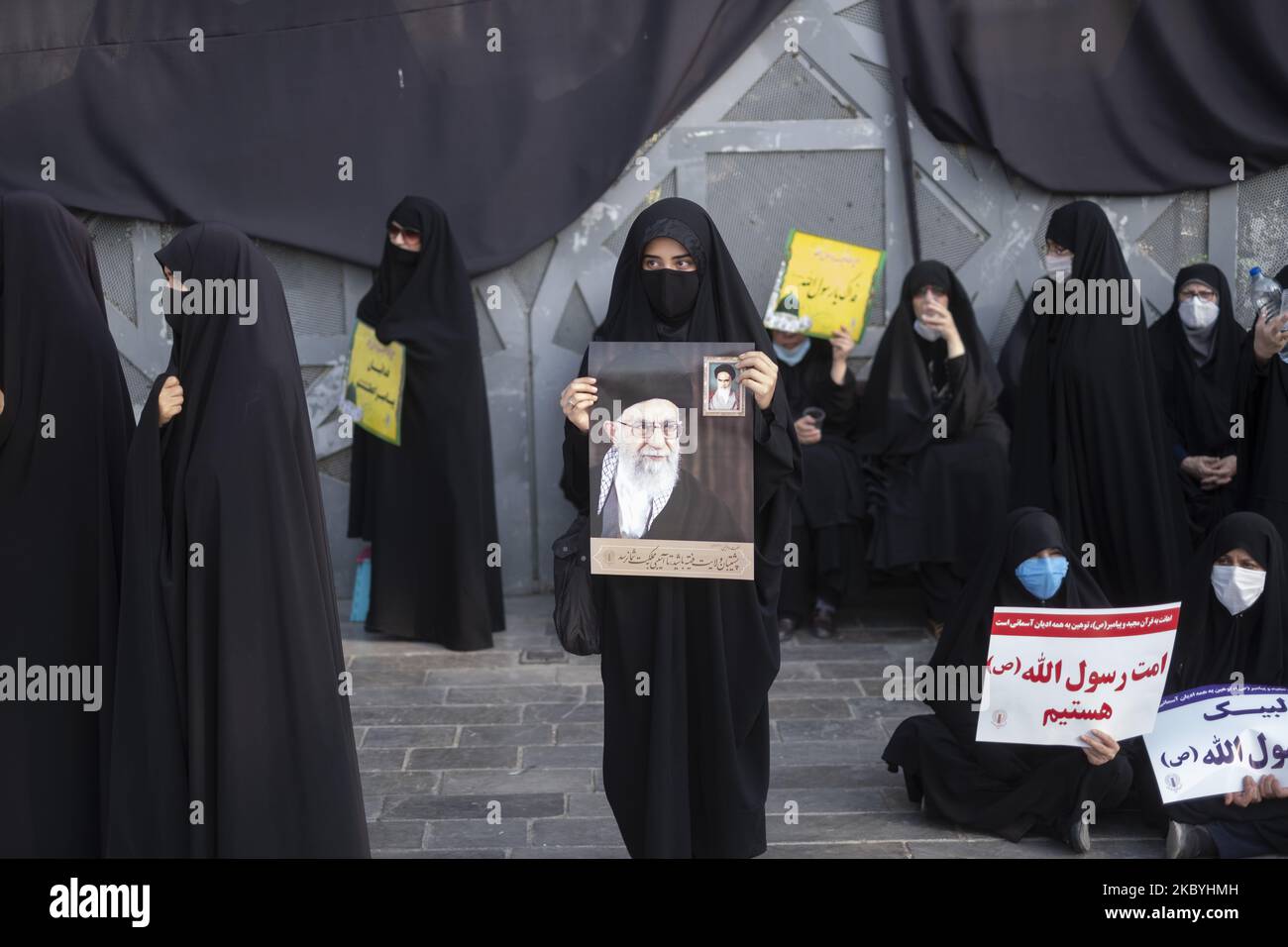 An Iranian veiled woman wearing a protective face mask holds portraits ...