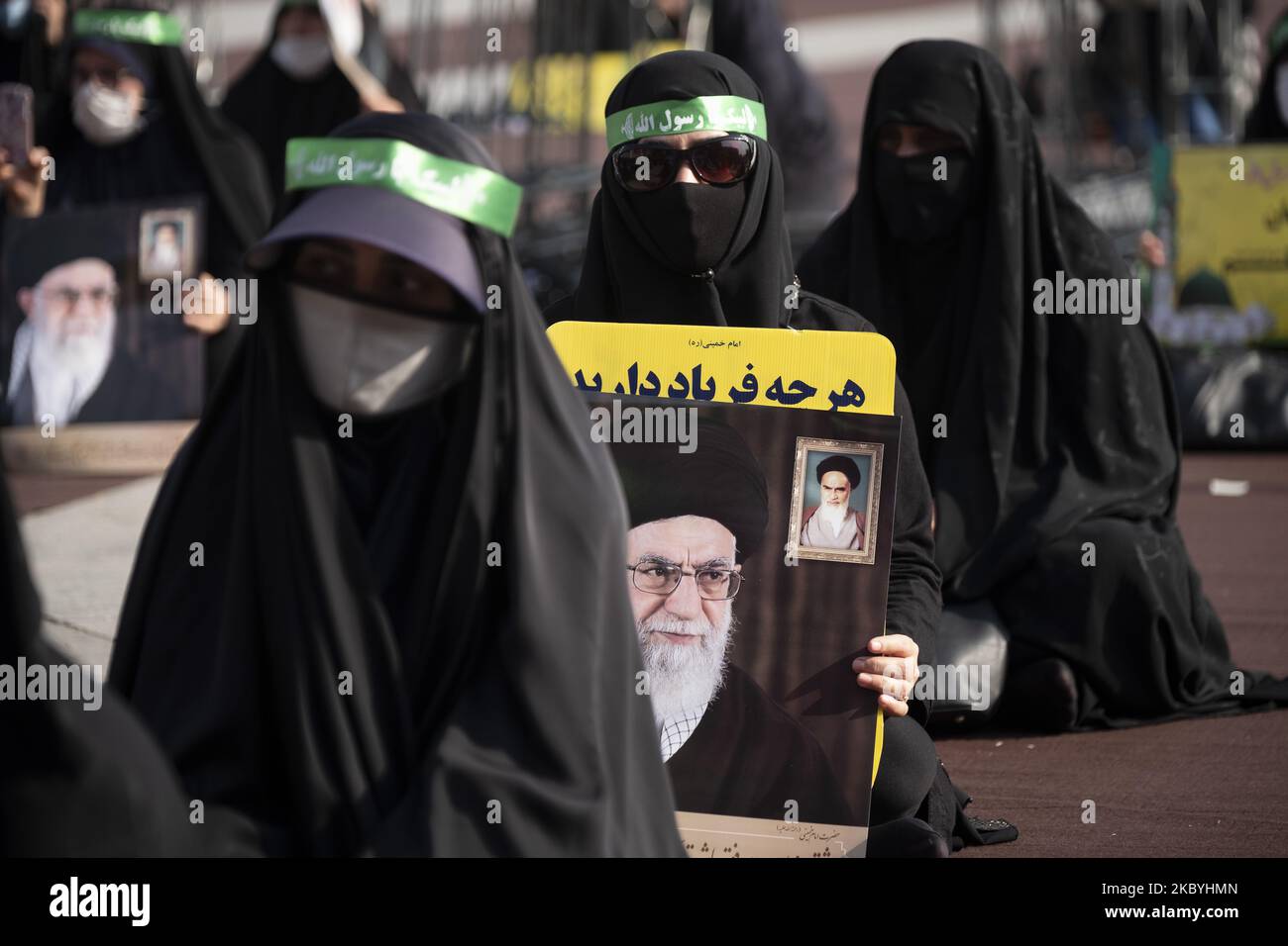 An Iranian veiled woman wearing a protective face mask holds portraits ...