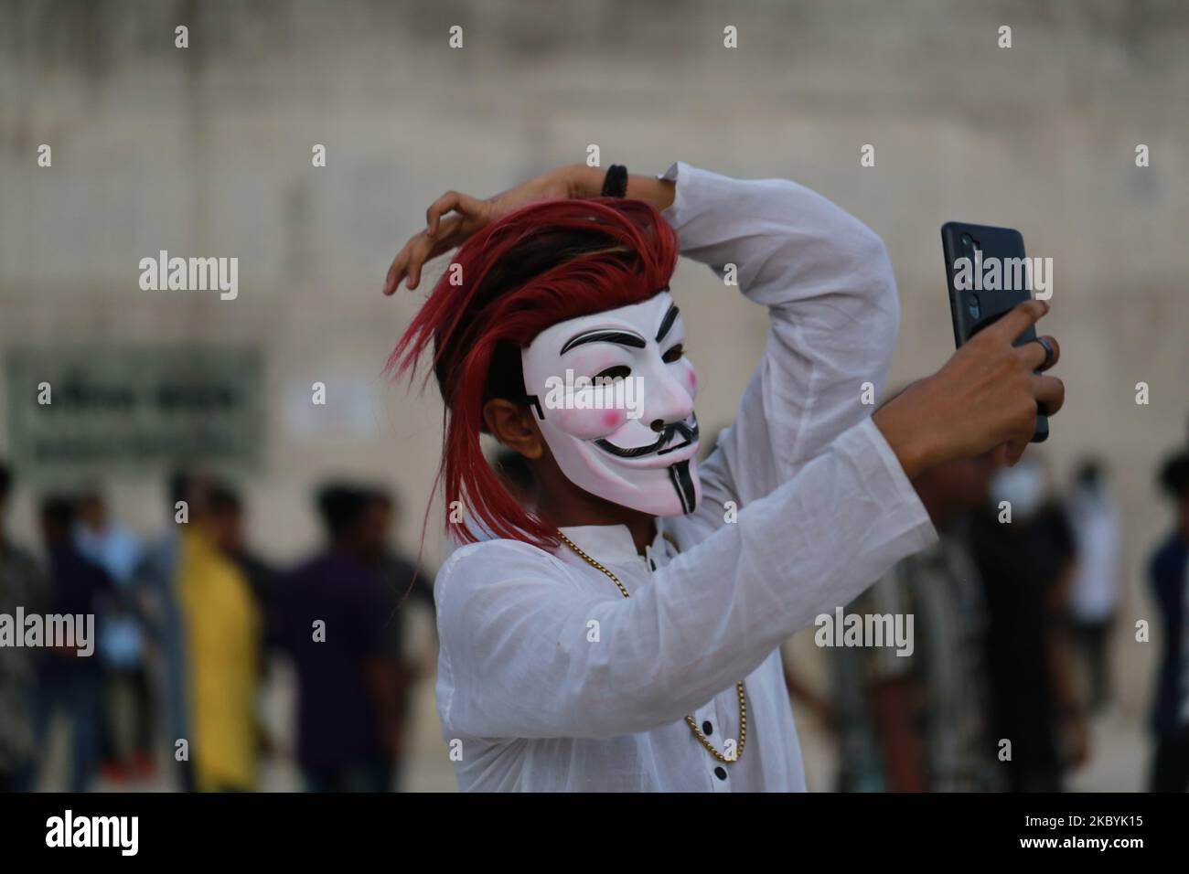 A boy wearing face mask poses for a photograph as he making TikTok ...