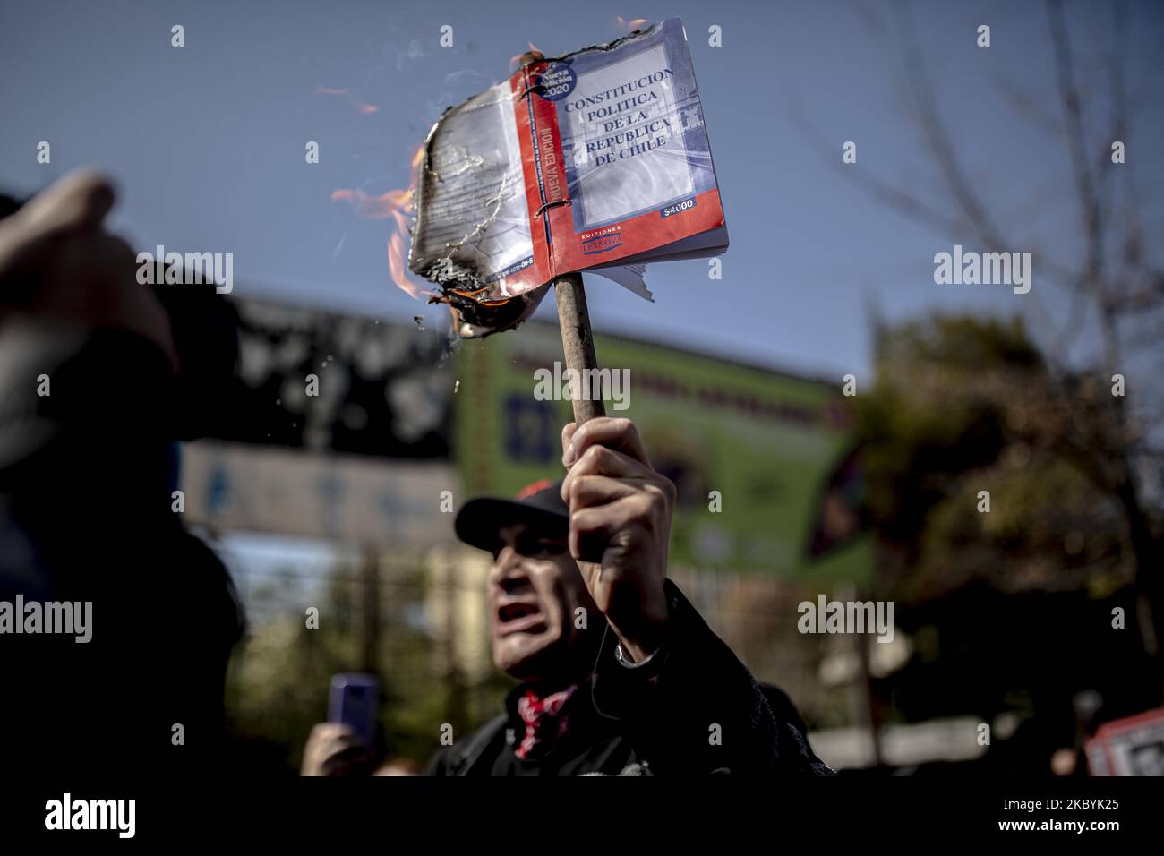 A demonstrator holds as he burns a Chilean constitution during a ...