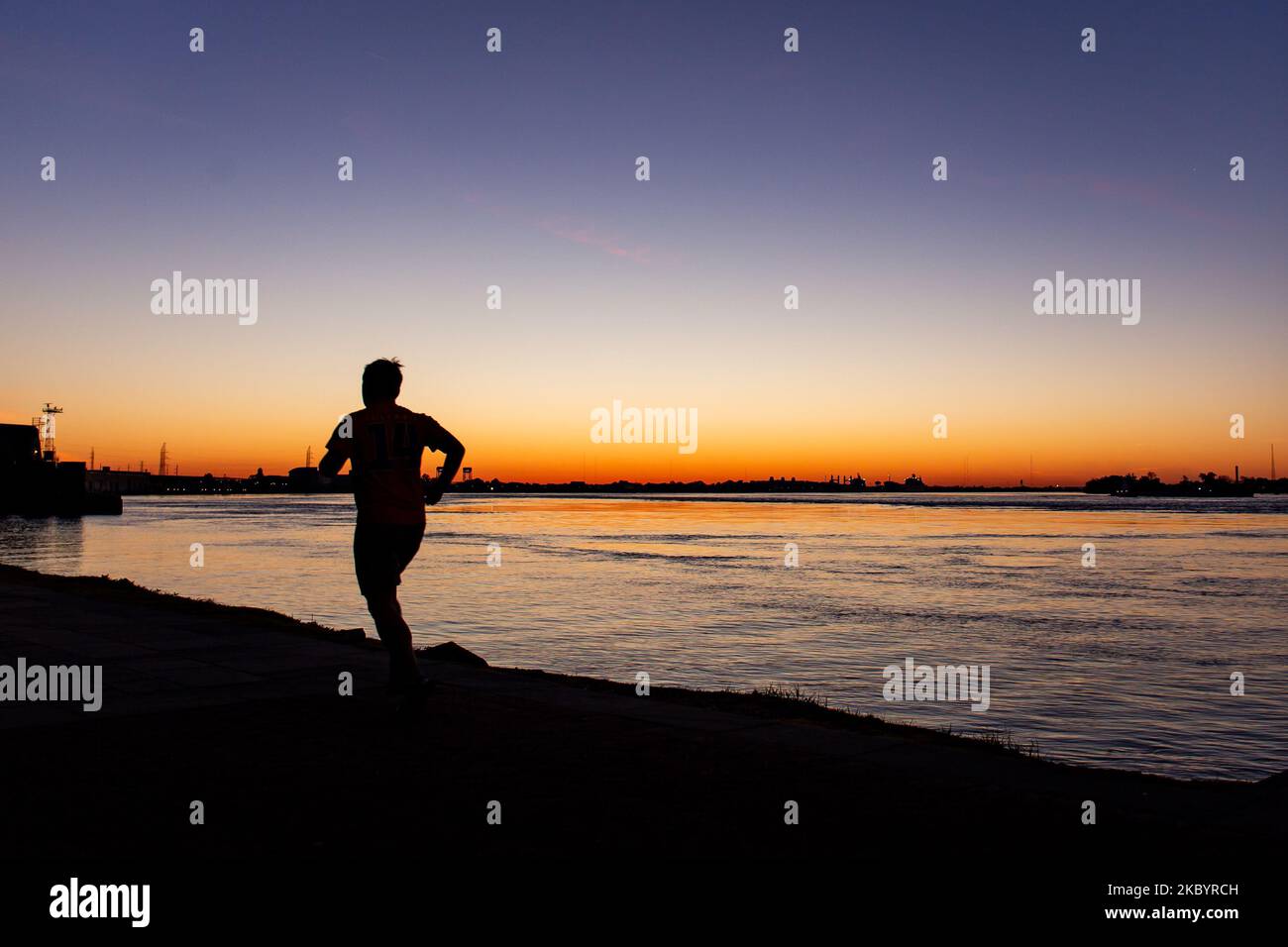 A jogger silhouette against sunrise on the Mississippi River Walk in ...