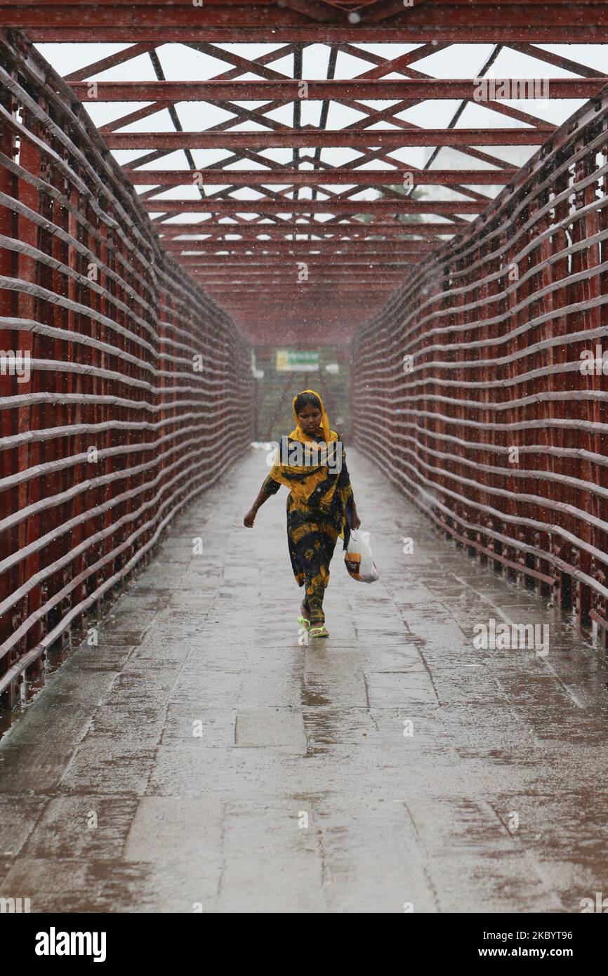 A woman walks on a foot over-bridge during the rainfall in Dhaka ...