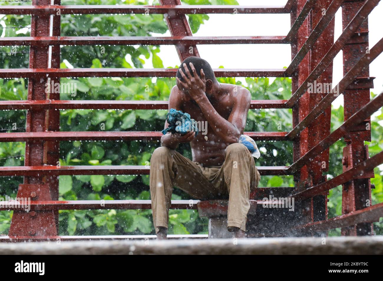 A man wet in the rain on a foot over-bridge during the rainfall in ...