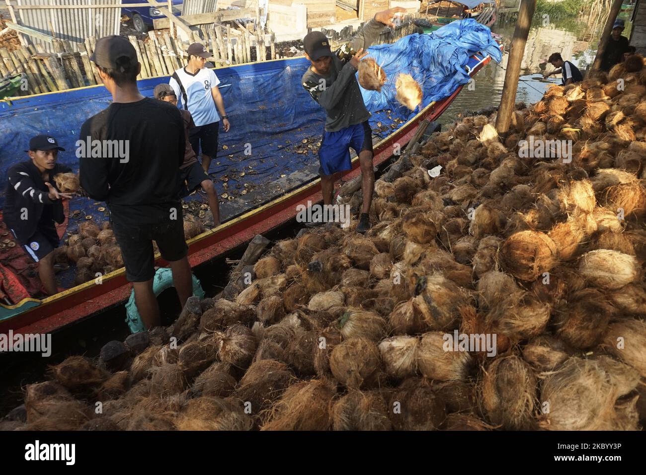 Loading and unloading activities on small boats, herding coconuts in ...