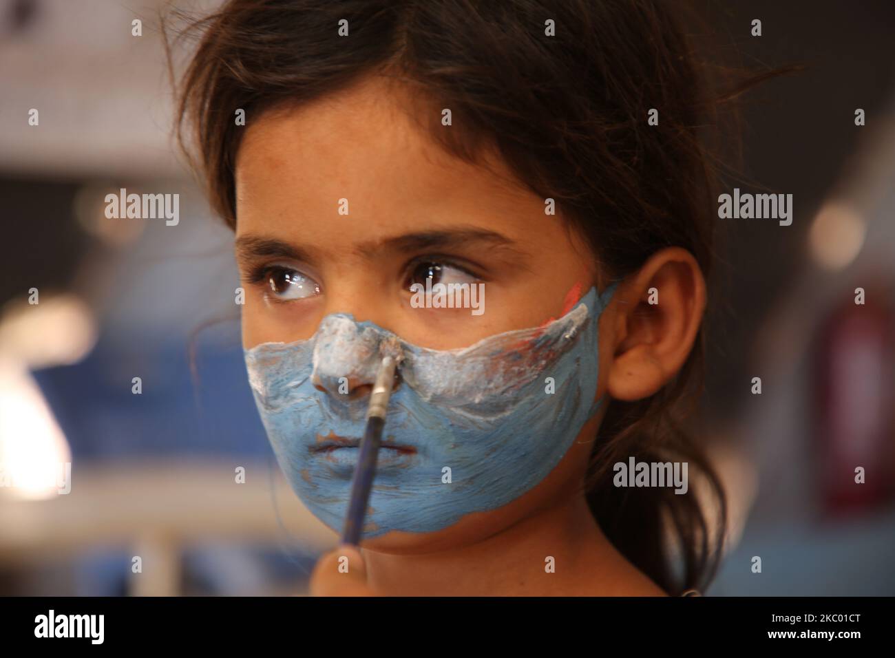 The young artist, Osama Alali, 13, draws masks on the faces of children ...