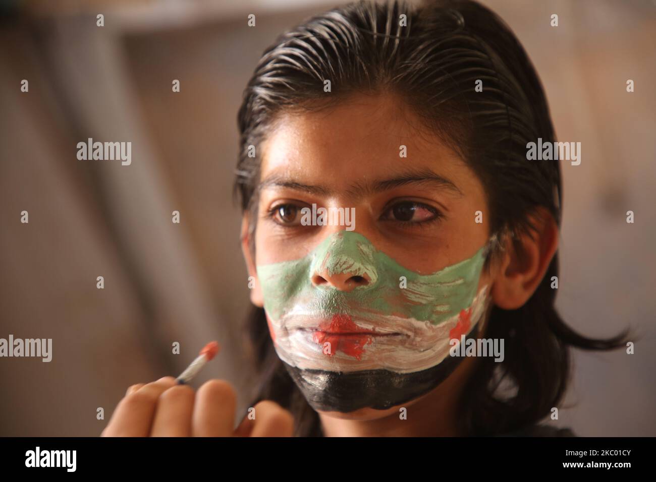 The young artist, Osama Alali, 13, draws masks on the faces of children ...