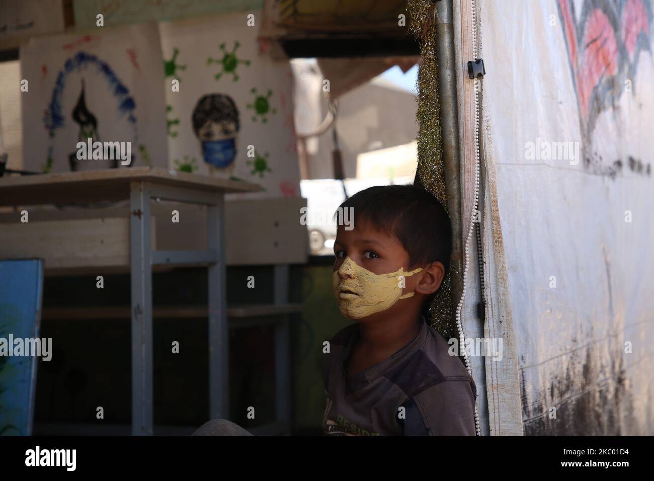 The young artist, Osama Alali, 13, draws masks on the faces of children ...