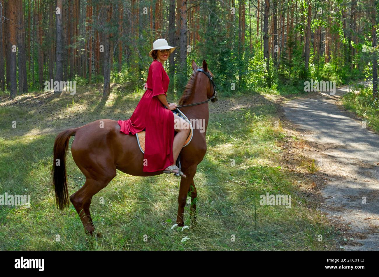 Woman in red dress rides a horse in early spring Stock Photo - Alamy