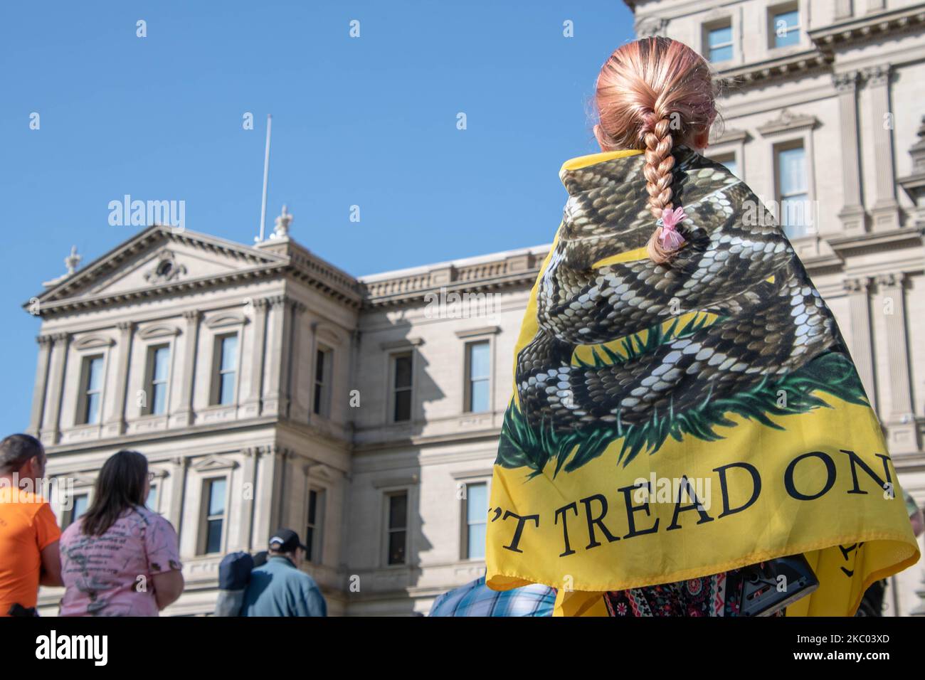 A young girl wraps herself in a Gadsen flag that states, "Don't Tread ...