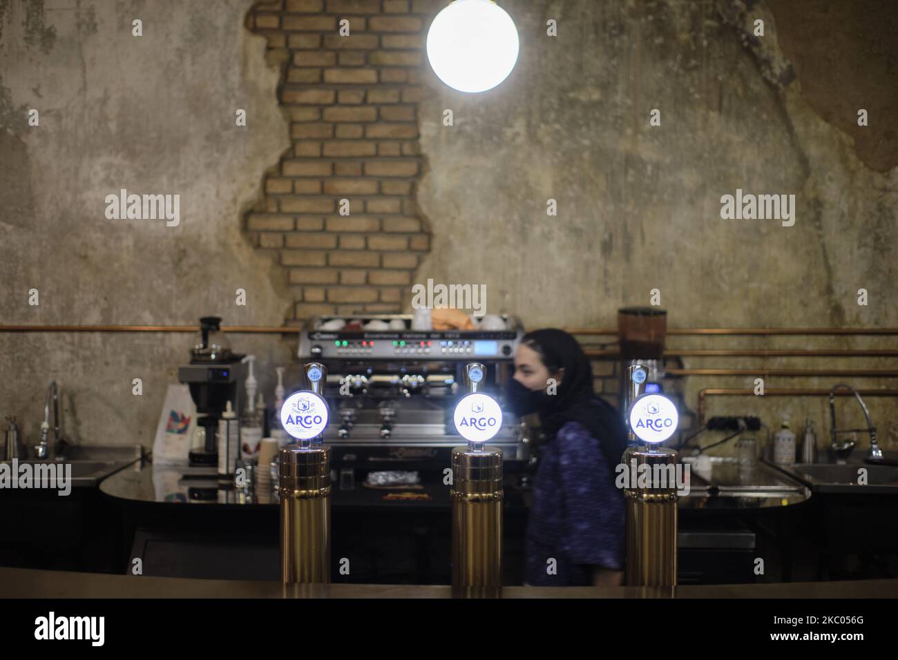 An Iranian cafe-woman wearing a protective face mask works at a cafe in ...