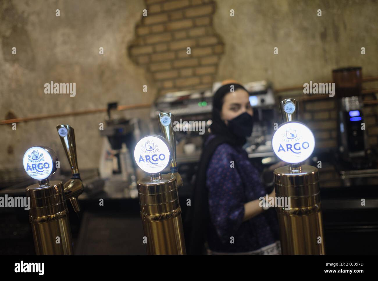 An Iranian cafe-woman wearing a protective face mask looks on as she ...