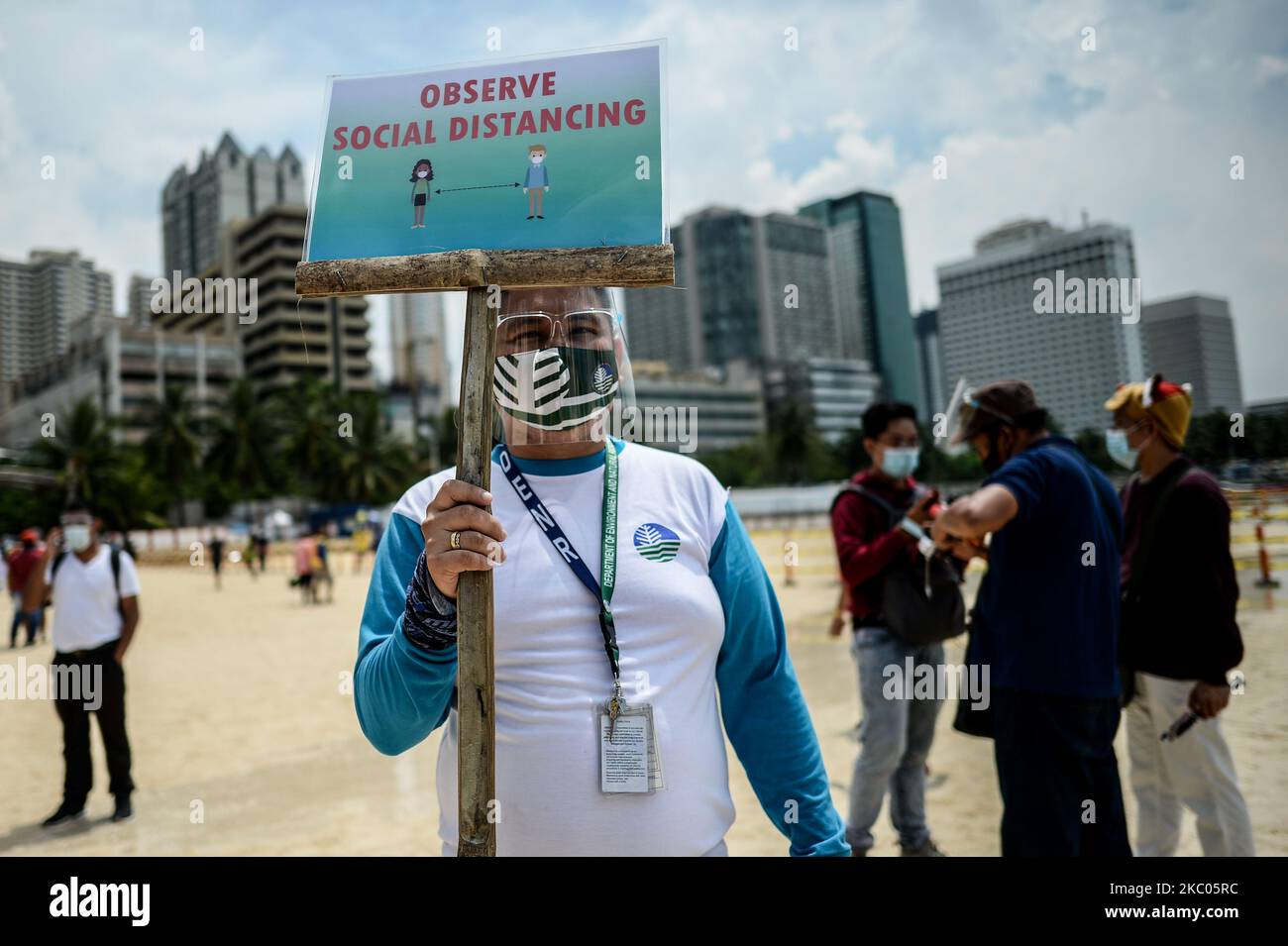 A government worker reminds people to observe social distancing at the ...