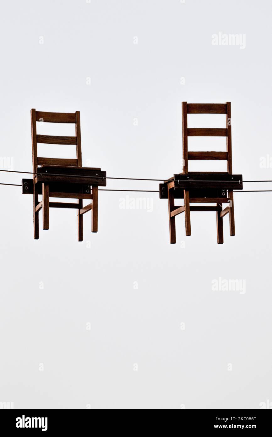 A vertical shot of two wooden chairs hanging on a rope isolated on a ...